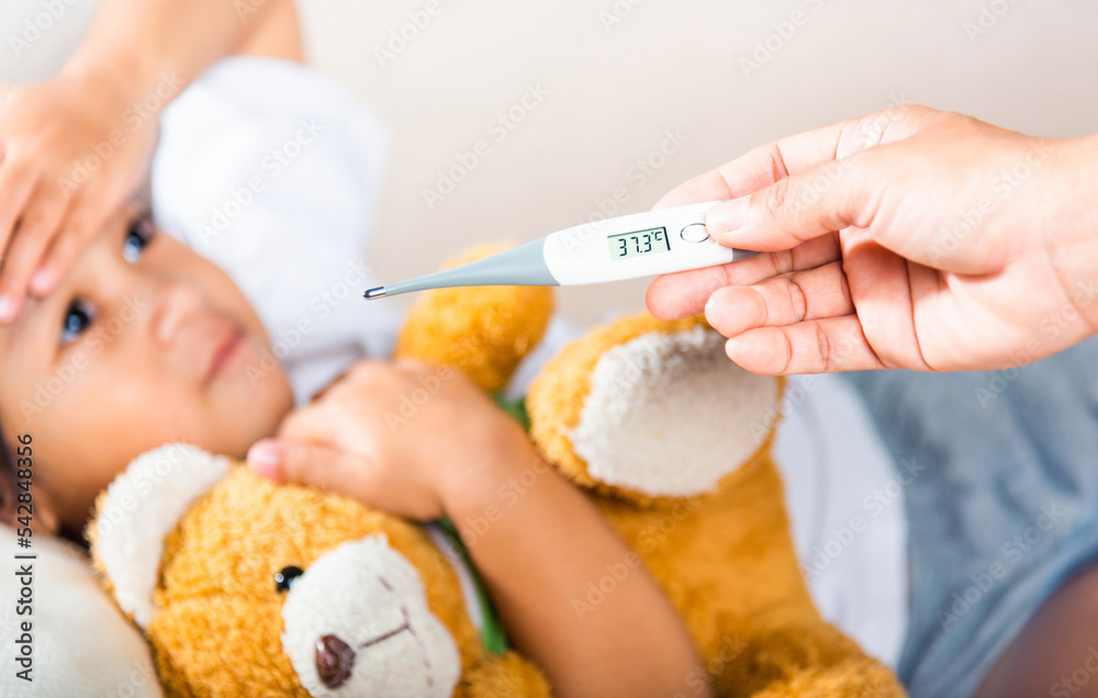 Sick kid. Mother parent checking temperature of her sick daughter with digital thermometer in ...