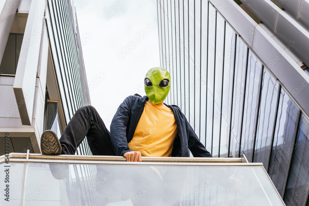 Man wearing alien mask jumping over railing in front of building Stock ...