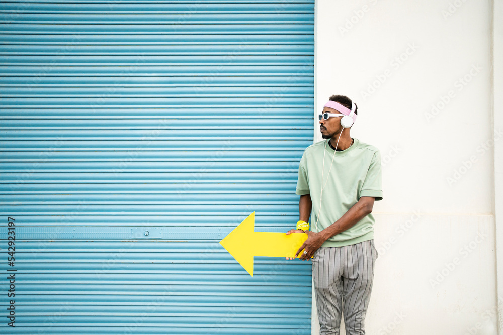 Man showing arrow sign standing by blue shutter Stock Photo | Adobe Stock