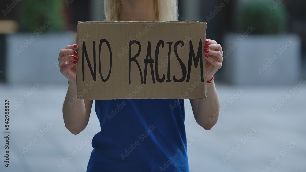 NO RACISM on cardboard poster in hands of female protester activist ...