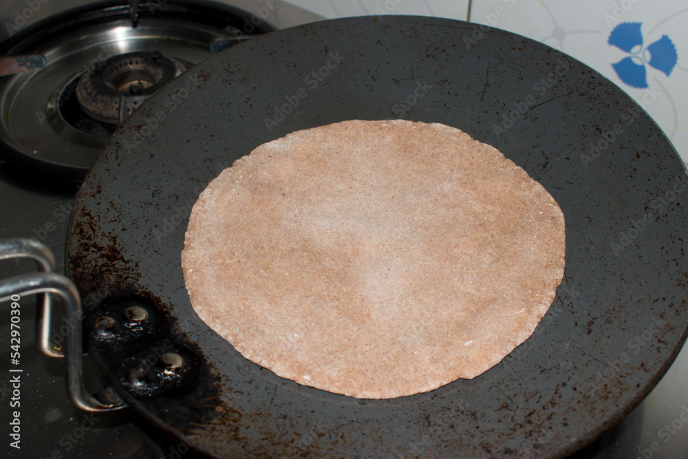 cooking round roti on tawa with the Dough of Ragi Nachni or finger ...