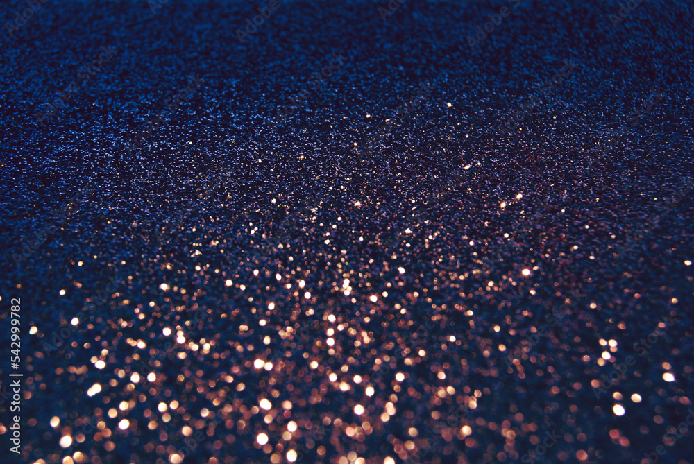 Dark blue de focused sparkle glitter background with golden particles ...