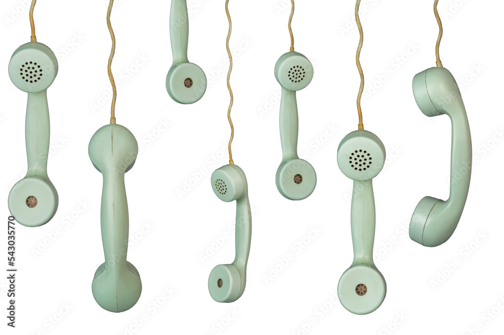 Many old telephone handsets from rotary landlines hanging from cords on ...
