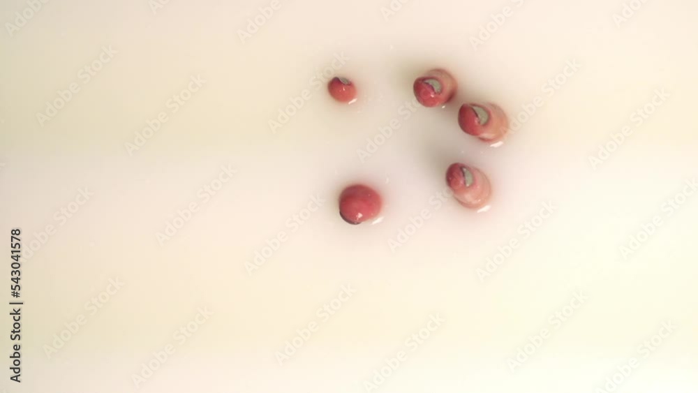 Close-up view of a hand coming out from a milk bath and sinking back ...