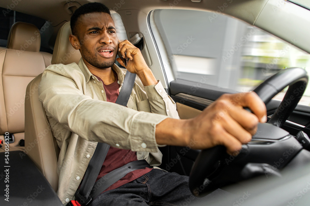 Foto de Angry african young man fighting on the phone while driving a ...