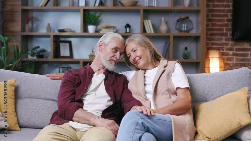 Mature Happy Couple Sitting On The Couch With Their Heads Bowed Gray