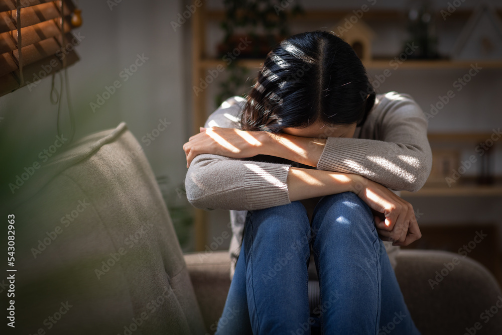 Sad or heart broken Asian woman or Asian girl sitting on a sofa in the ...