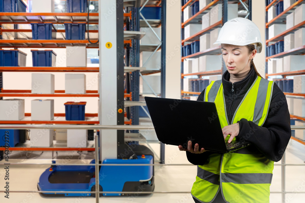 Warehouse operator. Woman with laptop. Girl manages automated warehouse ...