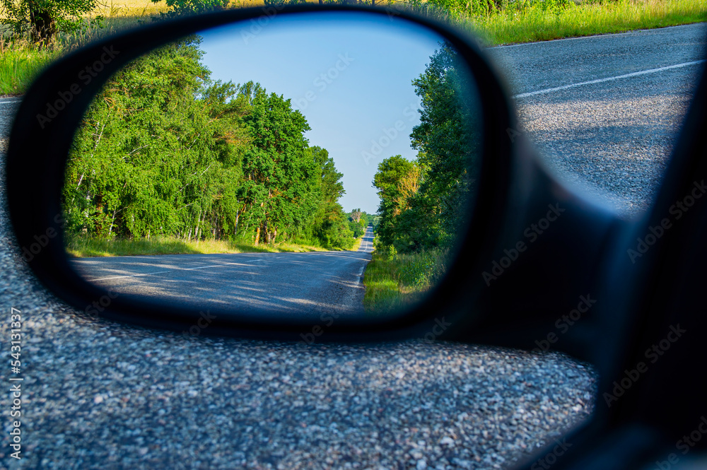 Reflection in the mirror of a car of a two-lane asphalt road with white ...