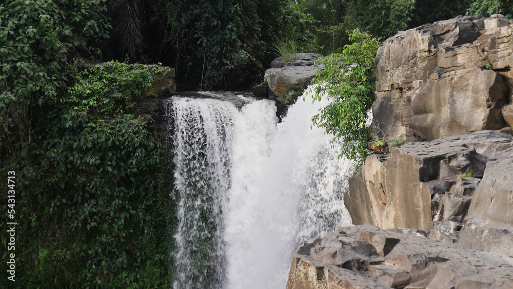 A large waterfall surrounded by jungle and rocky ledges filmed in ...
