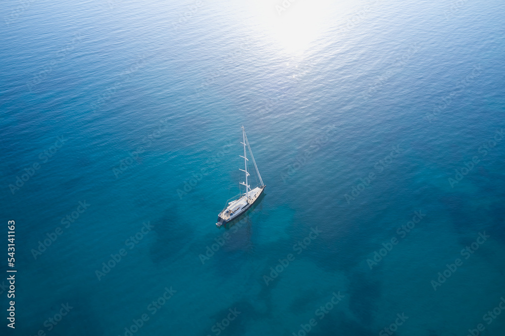 A large expensive high-speed sailing yacht is anchored on blue ...
