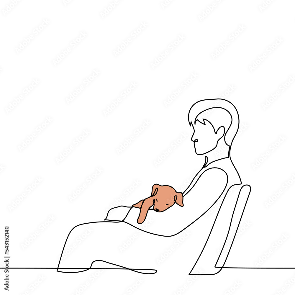 man sits in a chair with a sleeping ginger cute puppy in his arms and ...