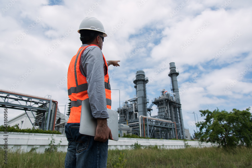 Engineer working and hand hold laptop at Power plant. People in PPE on ...