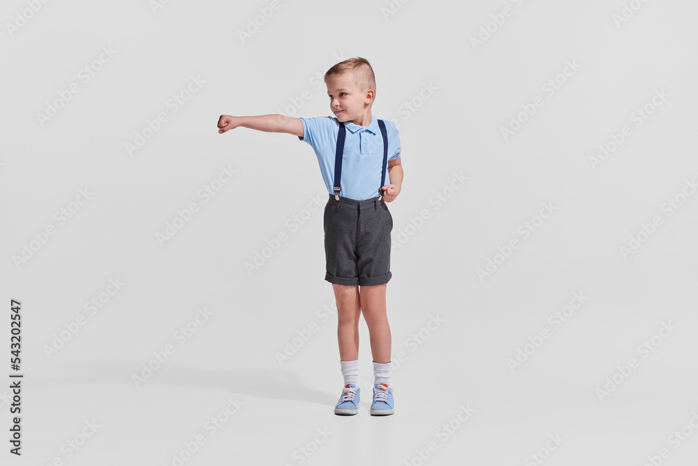 Portrait of cute little boy in short and shirt posing isolated over ...