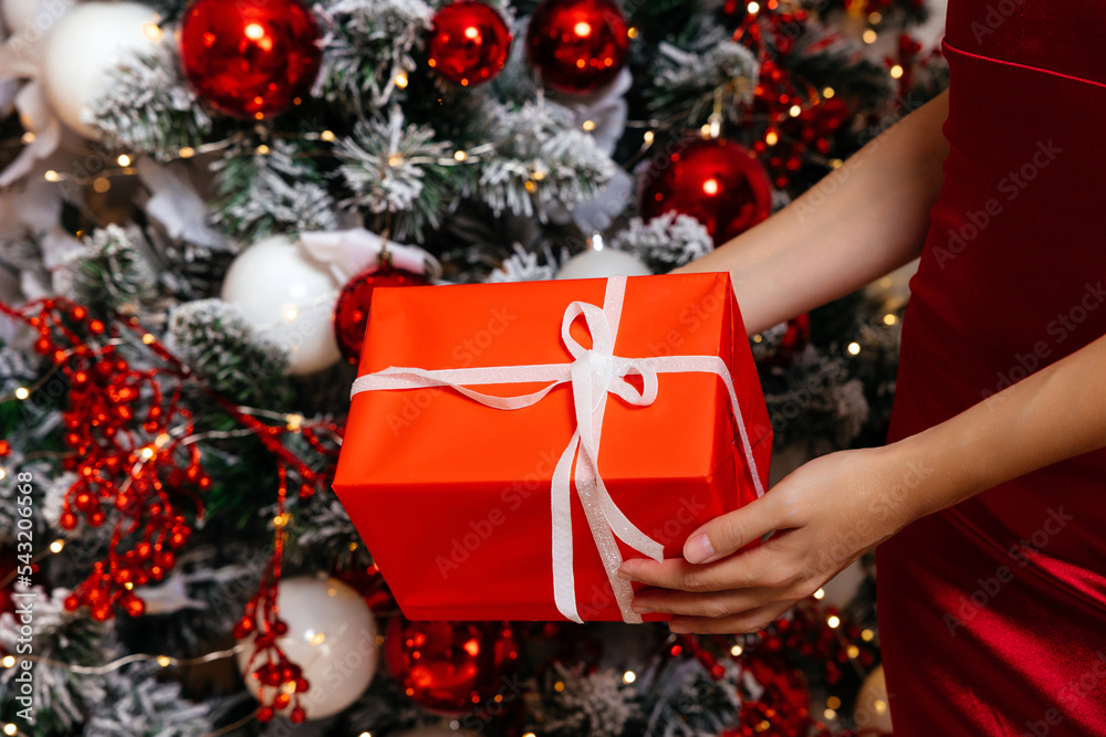 a girl in a red tight-fitting silk dress holds a gift wrapped in red ...