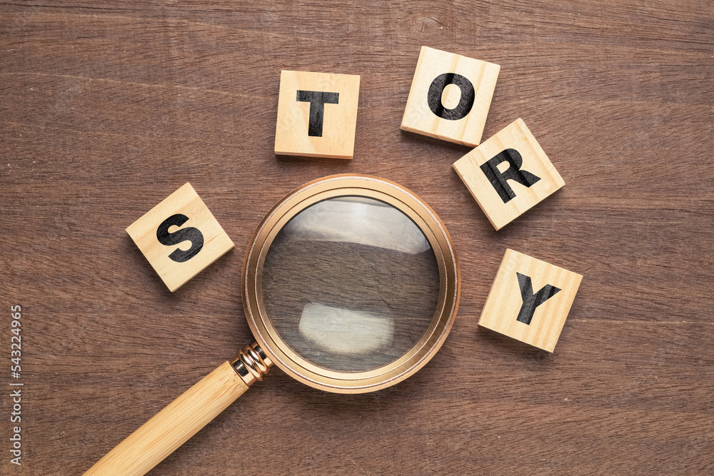 Magnifying glass with wood blocks of STORY word on woof background ...