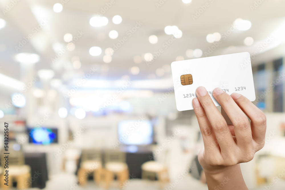 Hand using credit card for shopping at shopping mall building ...