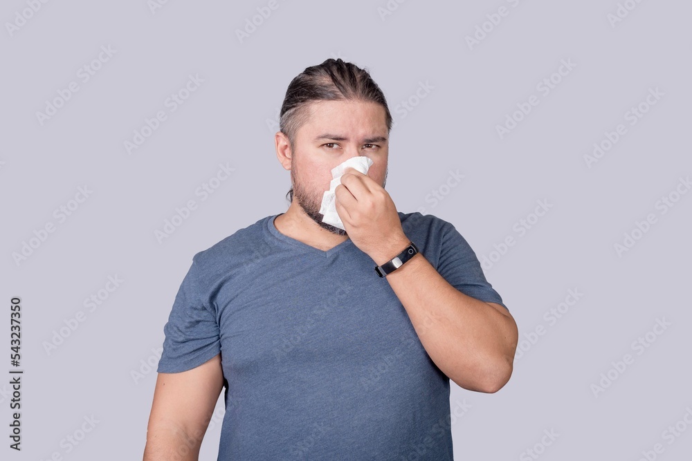 A man covering his nose with a piece of tissue paper. Suffering from a ...