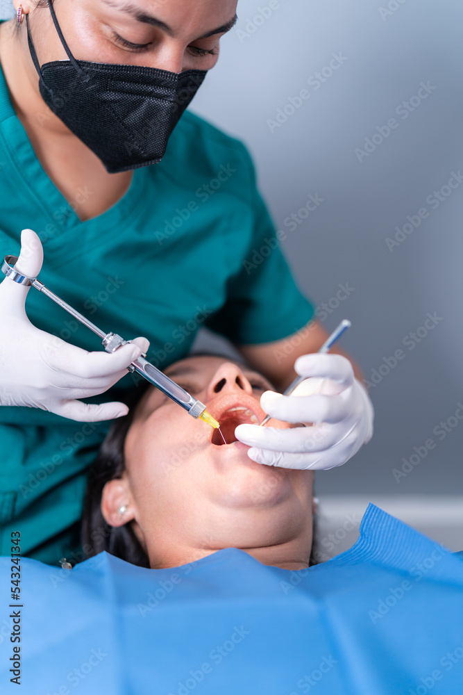 Anonymous orthodontist giving anesthesia to Hispanic female patient ...