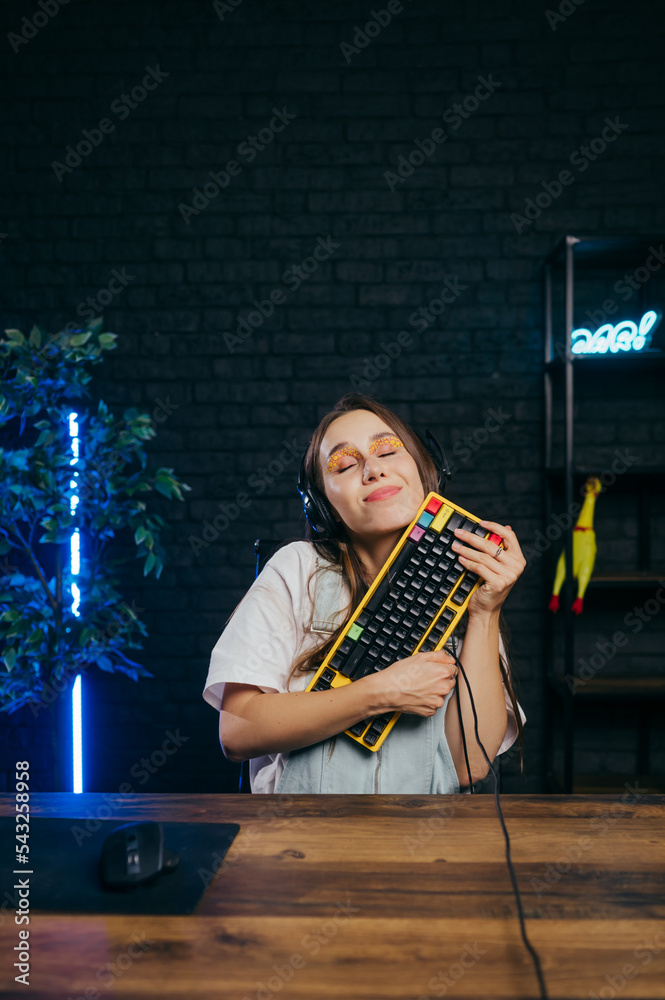 Cute girl streamer gamer is sitting at home at the computer at night ...