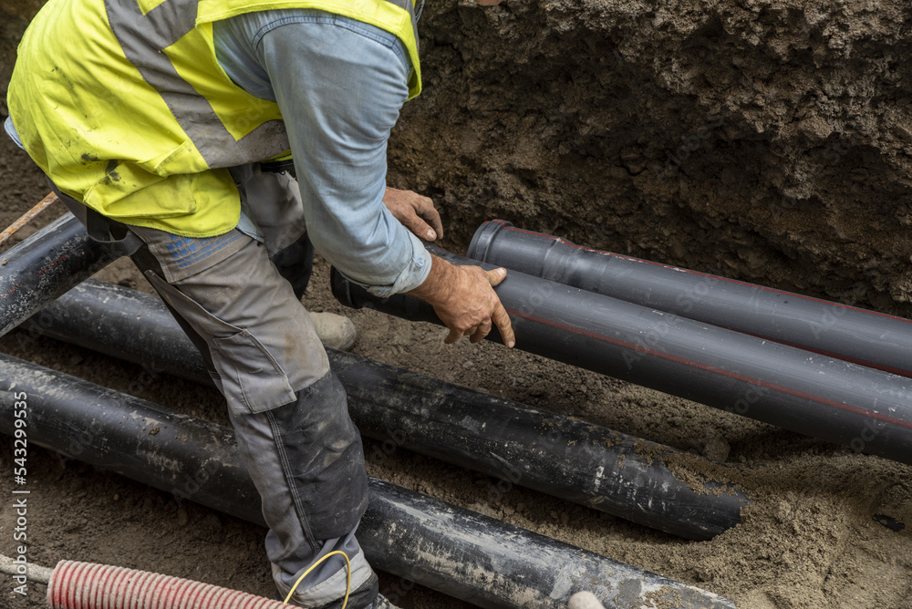 Workers install underground pipes for water, sewerage, electricity and ...