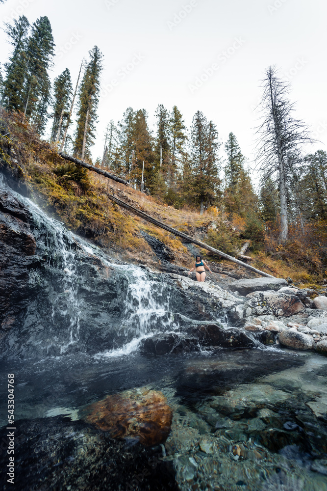 vertical image of Woman walking near cascading hot waterfalls to enjoy ...