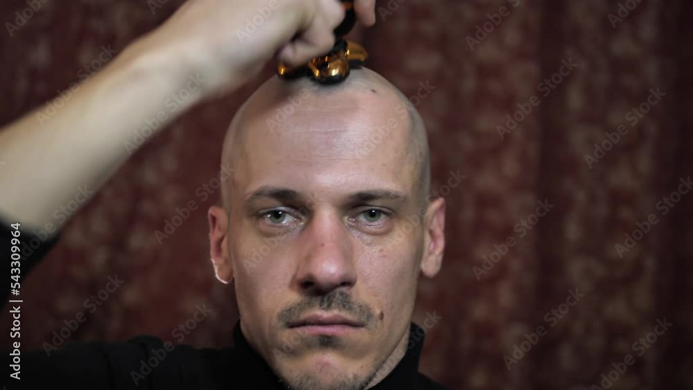 Portrait of a bald man who shaves his head with an electric razor ...