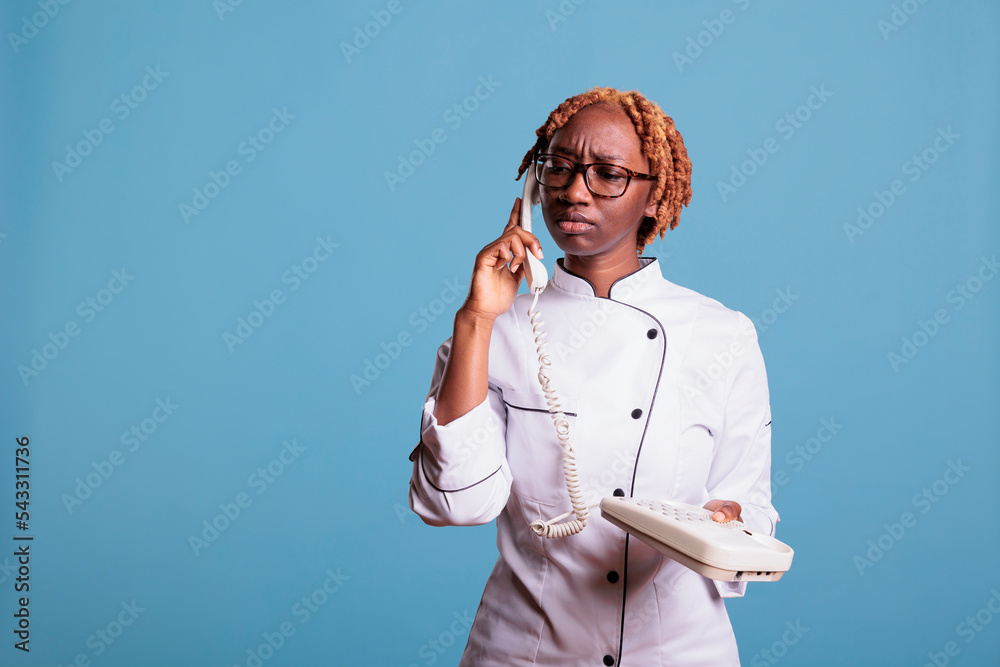 Female kitchen professional wearing uniform talking on white landline ...