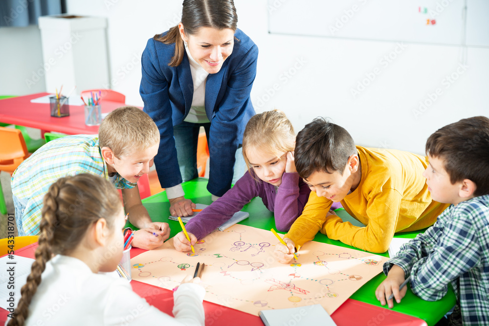 Teacher and collective of elementary age children draw together a board ...