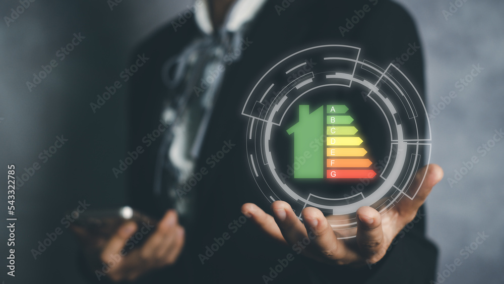 Person hand and house icon with energy efficiency scale image on black ...