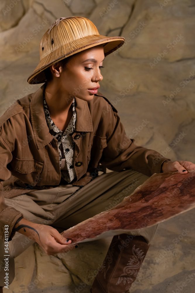 archaeologist in safari style outfit looking at ancient map while ...