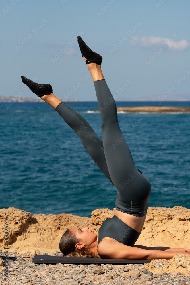 Malia, Crete, Greece. 2022. Pilates exercises on the beach . Shoulder ...