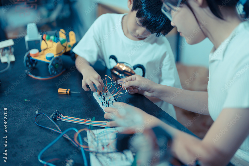 One young boy programming a robot with his science teacher on a primary ...