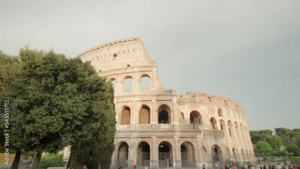 Lush green trees grow near large Colosseum on cloudy day in Rome ...