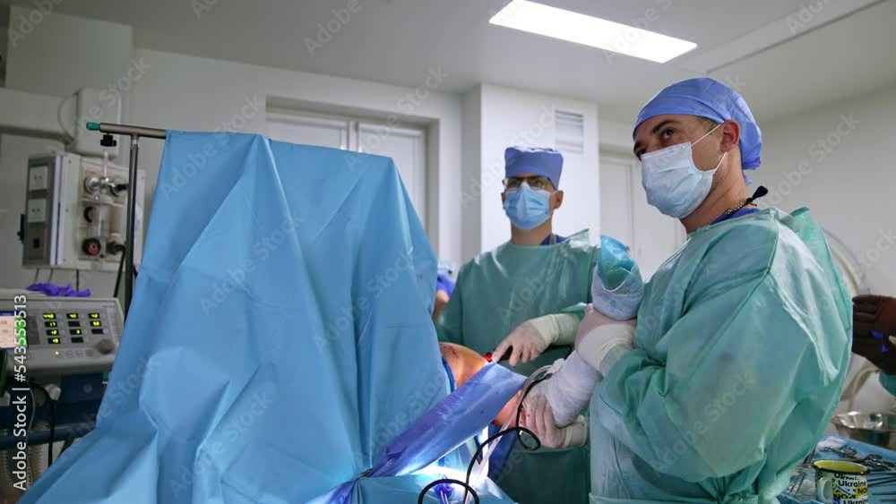 Surgeons in blue uniform conducting surgery using modern surgical ...