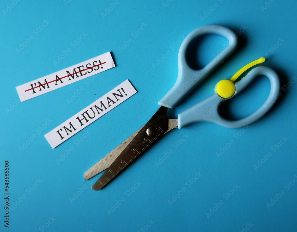 Scissors on blue background with handwritten two paper notes I AM A ...