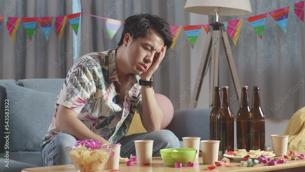 Drunk, Depressed Asian Man Sitting On A Sofa And Holding His Head With ...