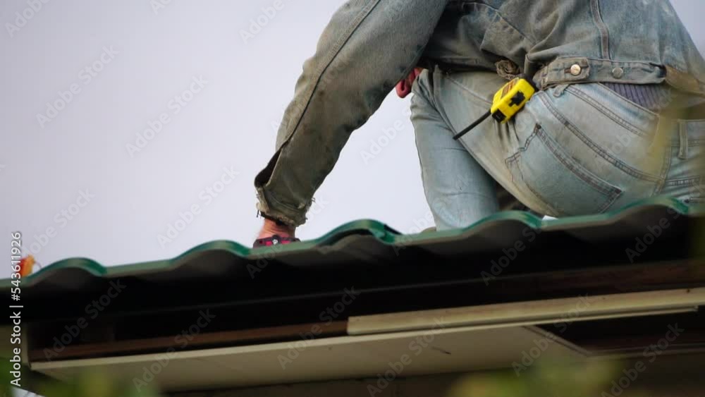 Renovation work. Professional roofer, man screws a screw into the roof ...