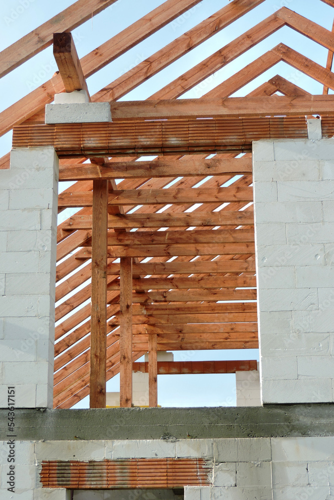 A timber roof truss in a house under construction, walls made of ...