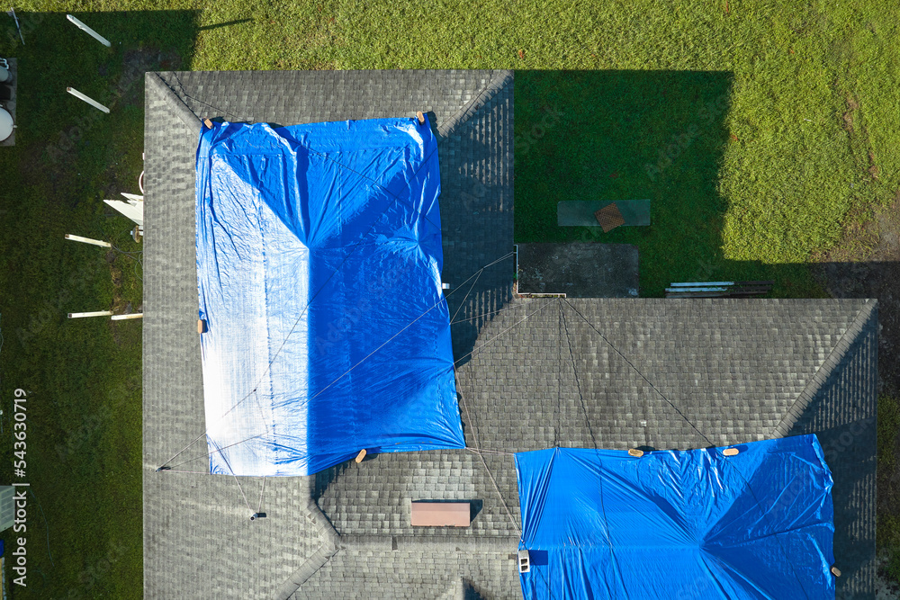 Top view of leaking house roof covered with protective tarp sheets ...