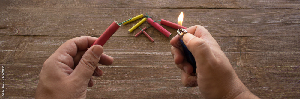 Image of the hands of a man who lights the fuse of a firecracker with a ...
