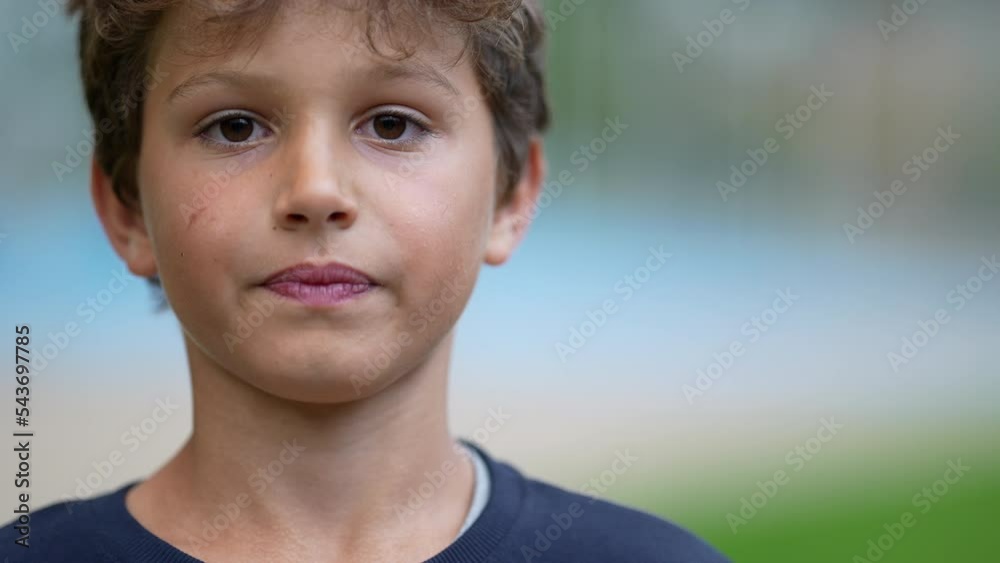 Portrait of a young boy standing outside turning head to camera. Pre ...