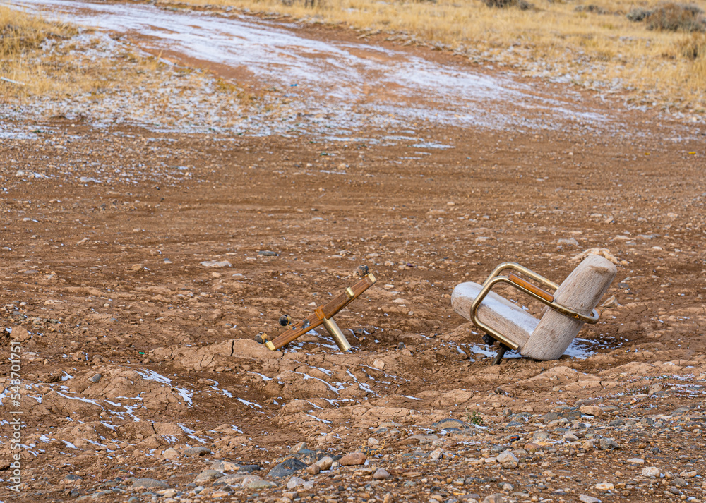 Stockfoto med beskrivningen Broken chair thrown away. Stuck in mud ...