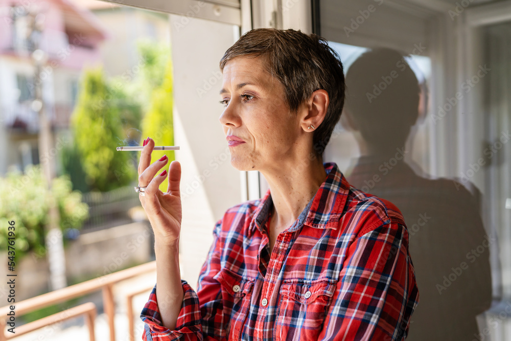 One woman mature or senior female smoking cigarette by the window at ...