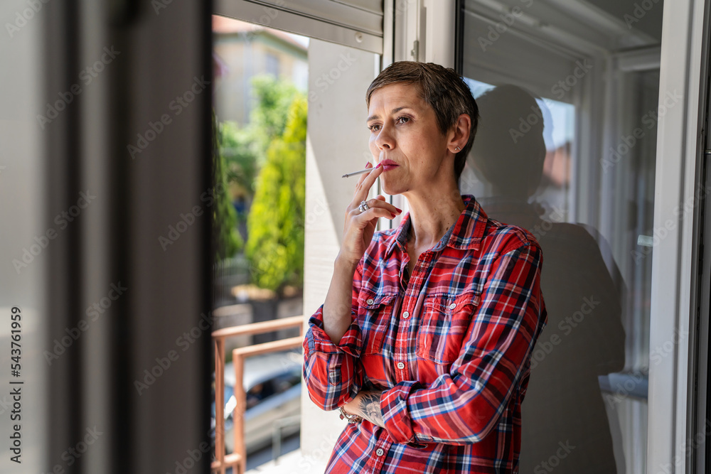 One woman mature or senior female smoking cigarette by the window at ...