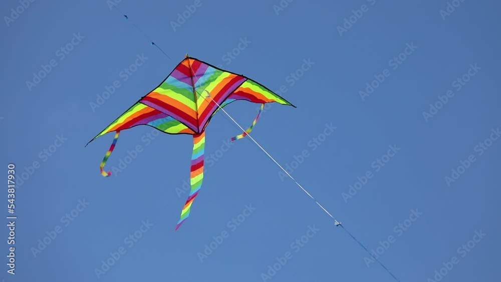 kite with the colors of the rainbow flying in the sky tied to a string ...