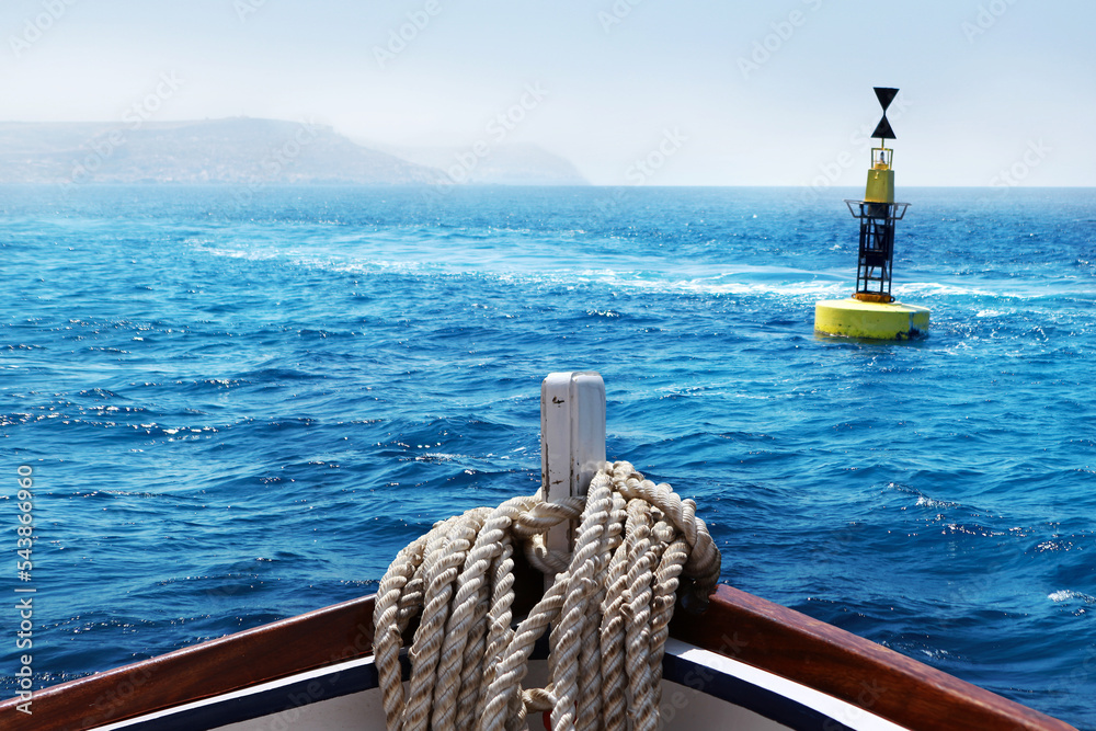 A wooden boat floating in the sea. The yellow and black steel ...