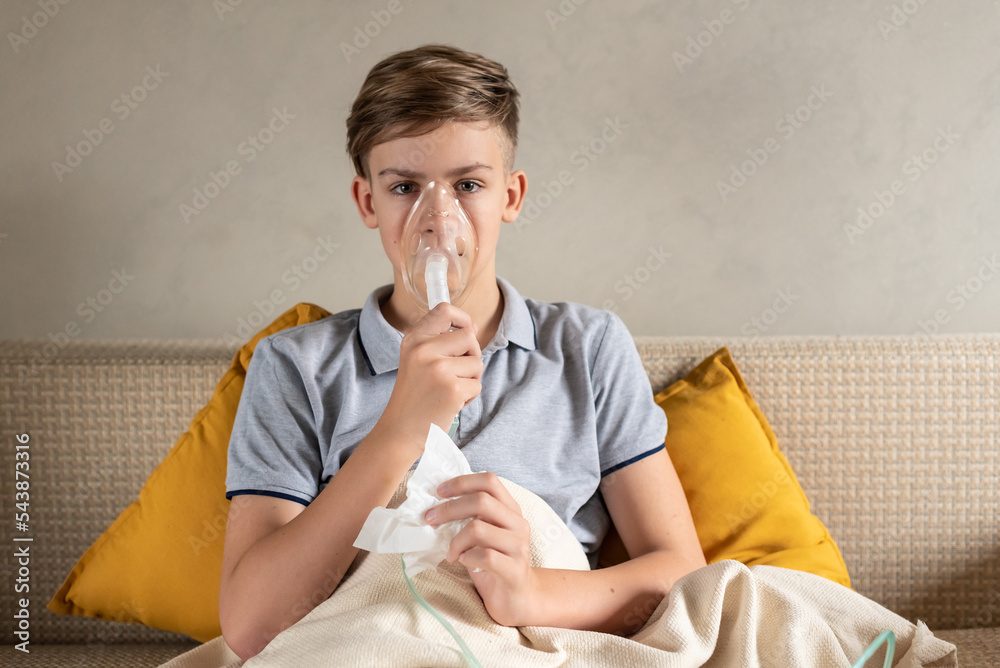 Sick teen boy with an inhaler. Unhealthy child doing inhalation at home ...