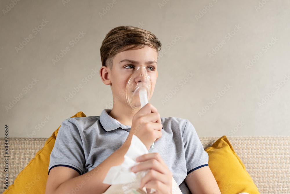 Sick teen boy with an inhaler. Unhealthy child doing inhalation at home ...