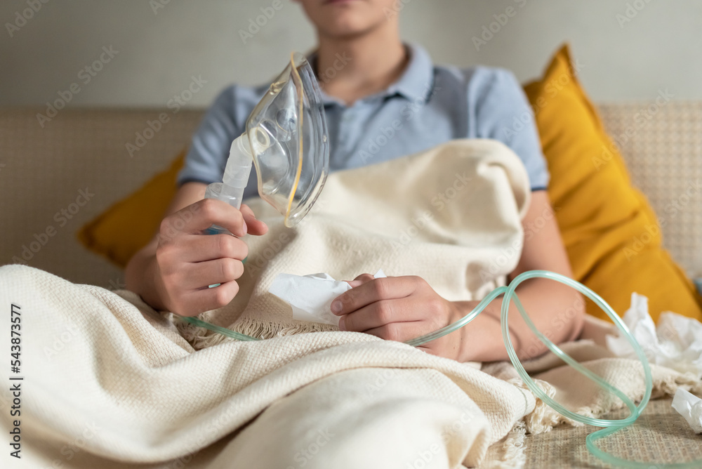 Sick teen boy with an inhaler. Unhealthy child doing inhalation at home ...